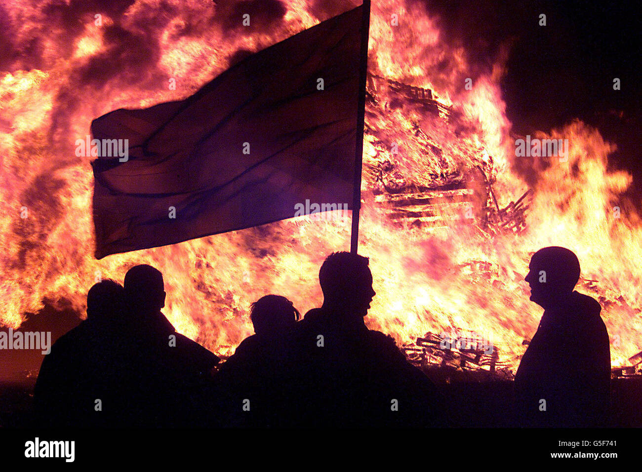 Loyalists hold a Union Jack flag at a bonfire lit at midnight in the ...