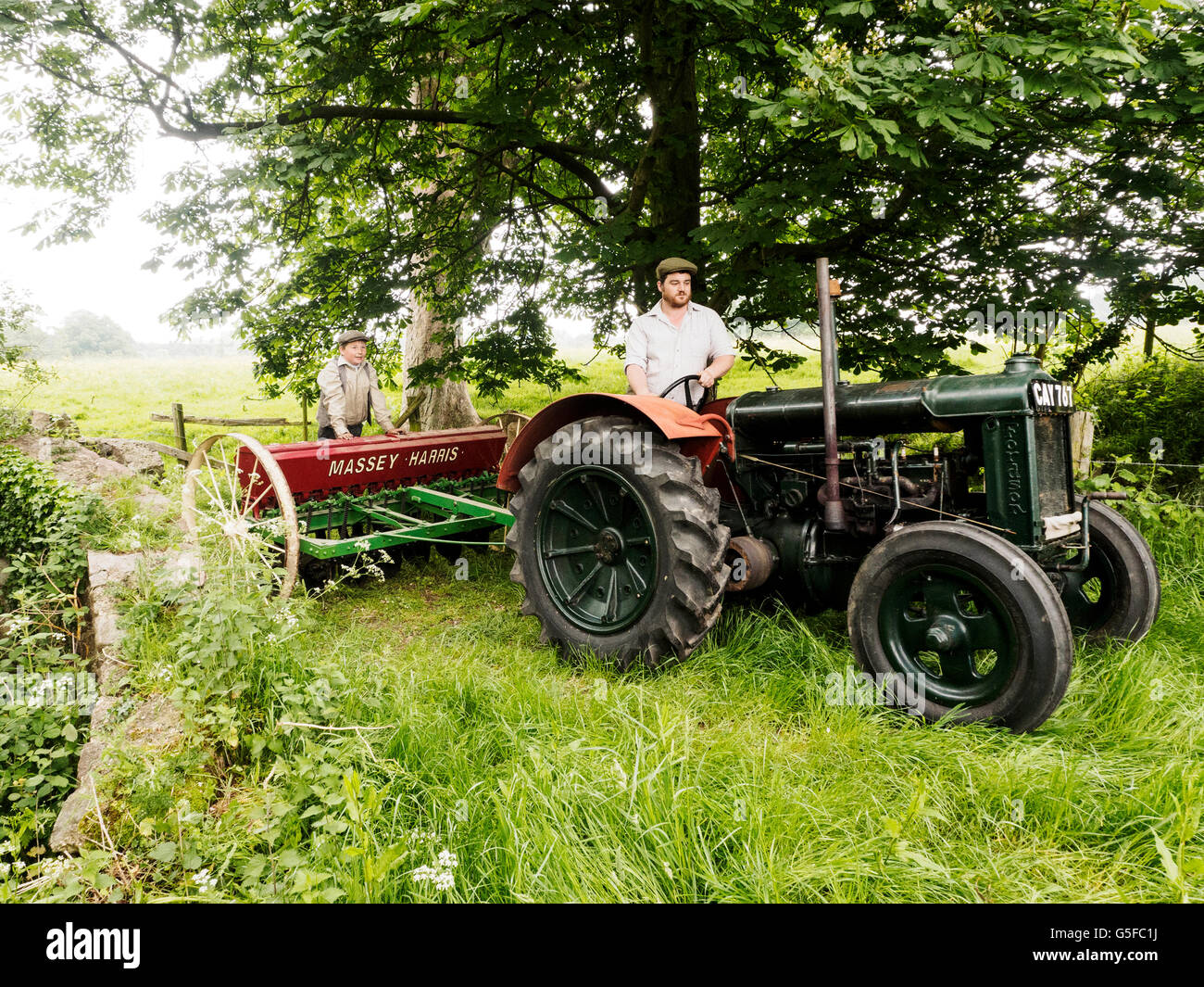 Farmer and farm boy in 1940's clothing with early Fordson Major tractor ...