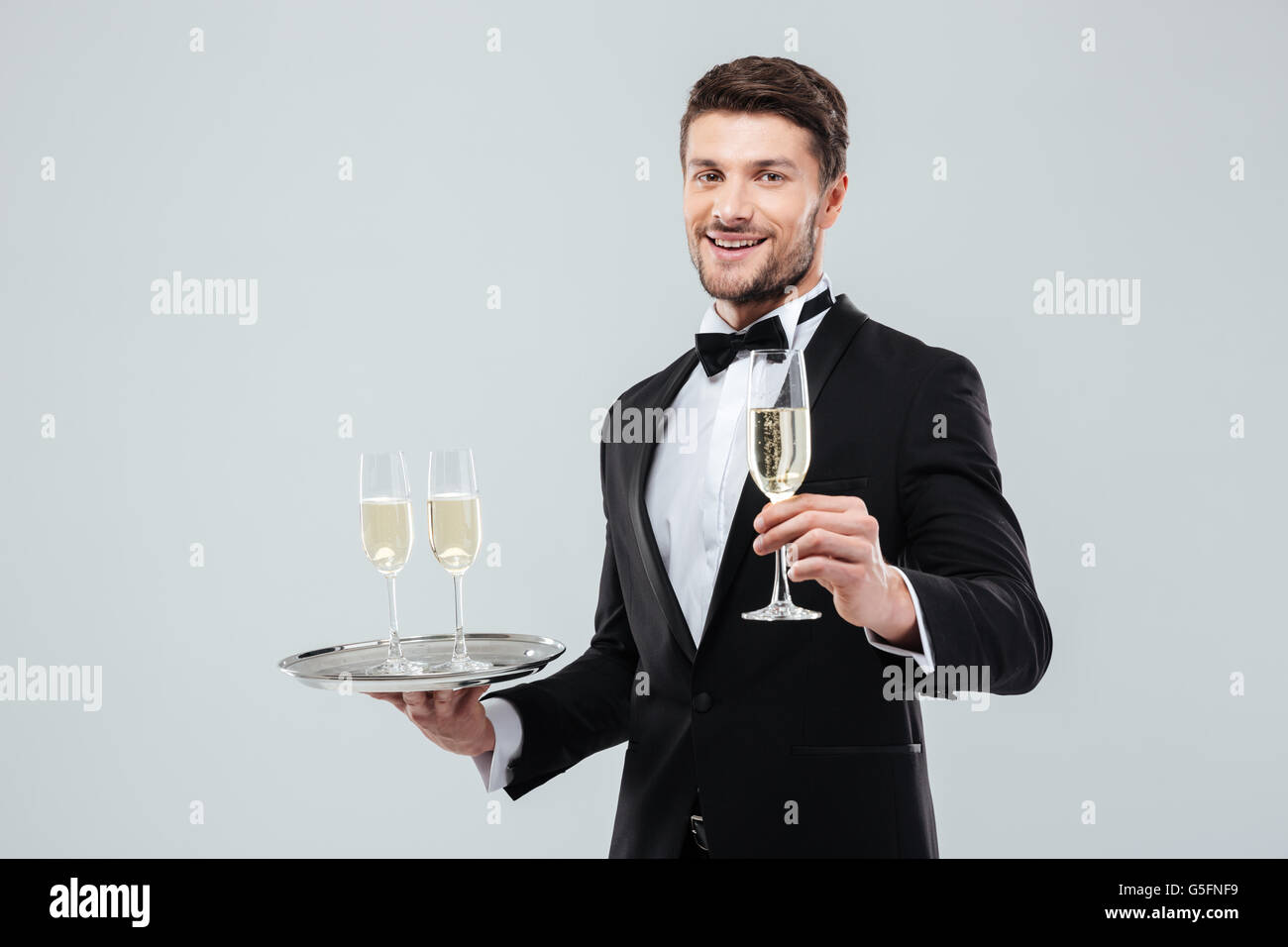 Happy young butler in tuxedo holding tray and glass of champagne Stock ...