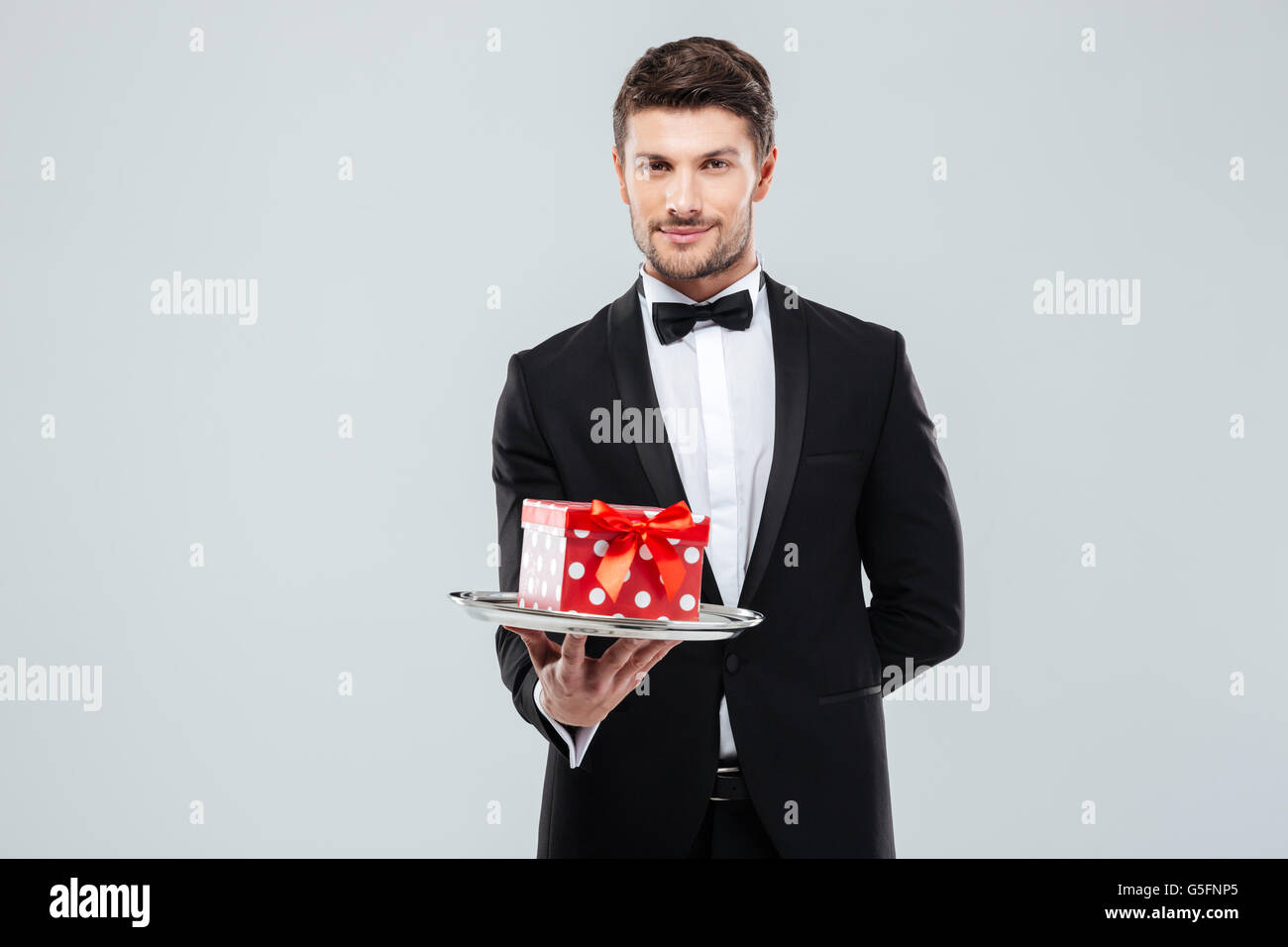 Handsome young butler in tuxedo with bowtie gift box on tray Stock ...
