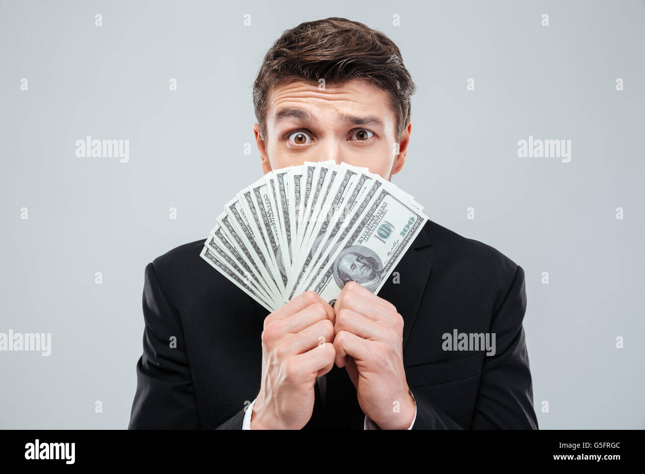 Confused young businessman covered his face with money over white ...