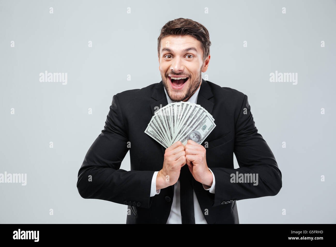 Cheerful excited young businessman laughing and holding money over ...