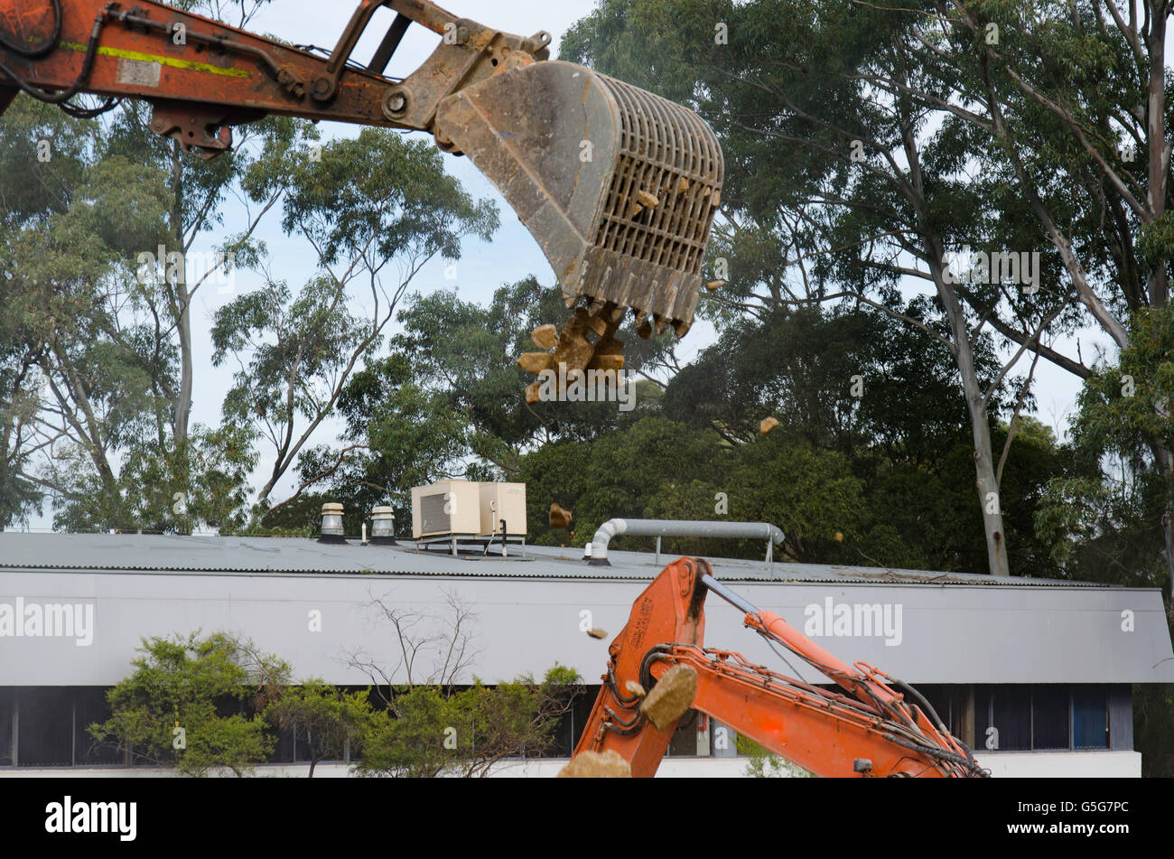 A raised arm of a diesel excavator empties a load of rock and rubble on ...