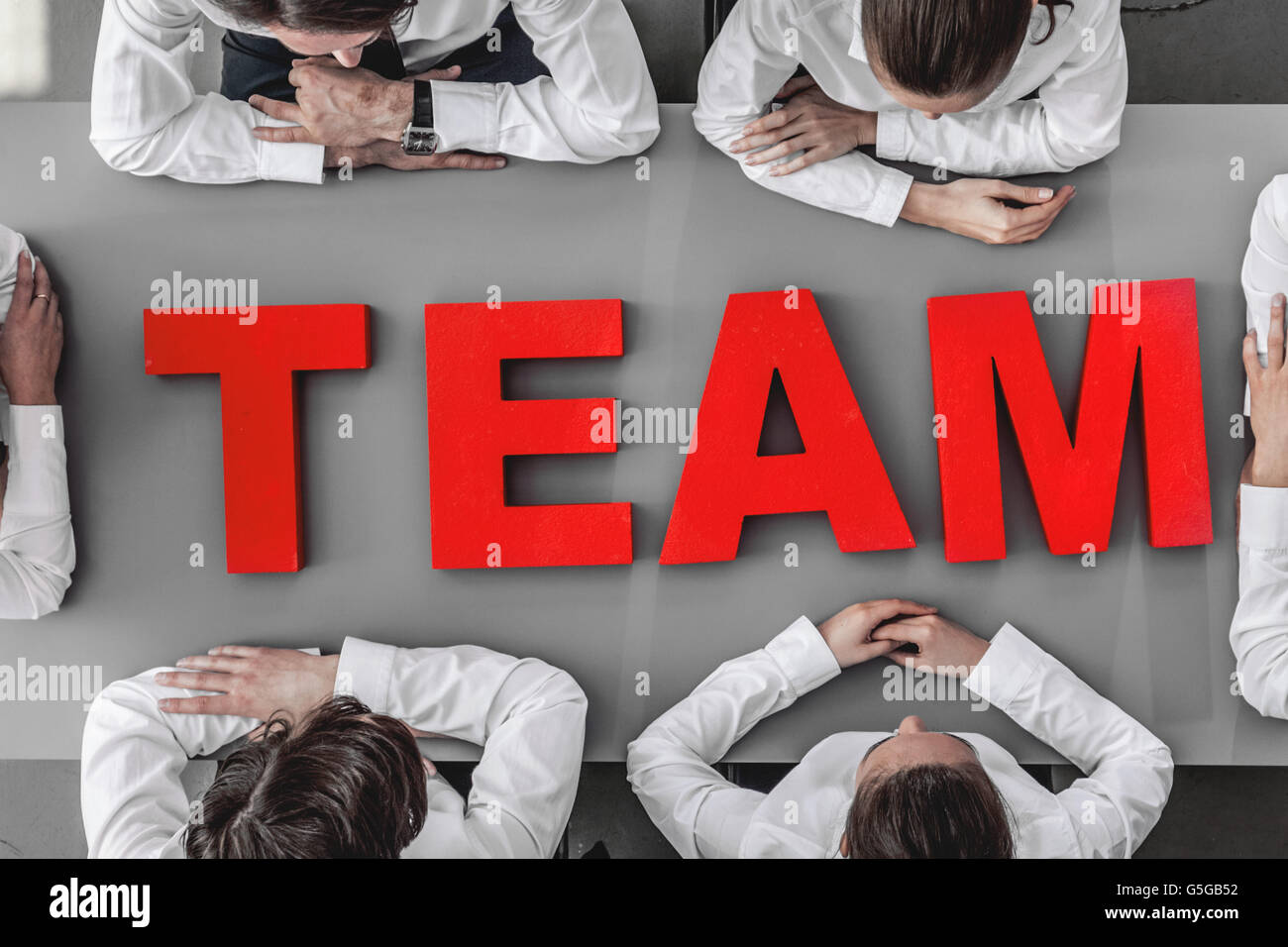 Business people sitting around the table with red letters TEAM ...