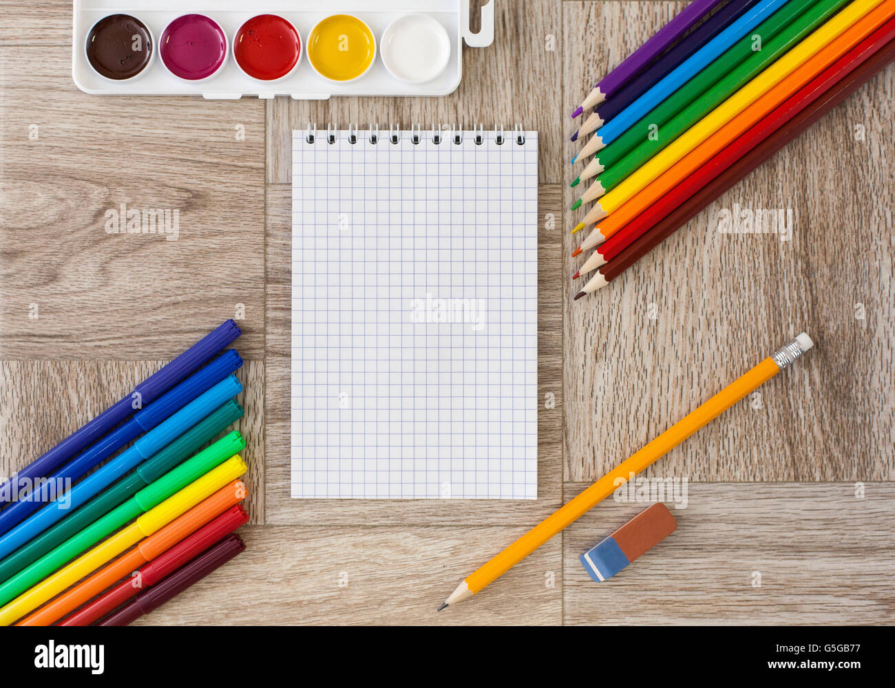 Lots of assorted colors marker pens and pencils with notepad, on wooden ...