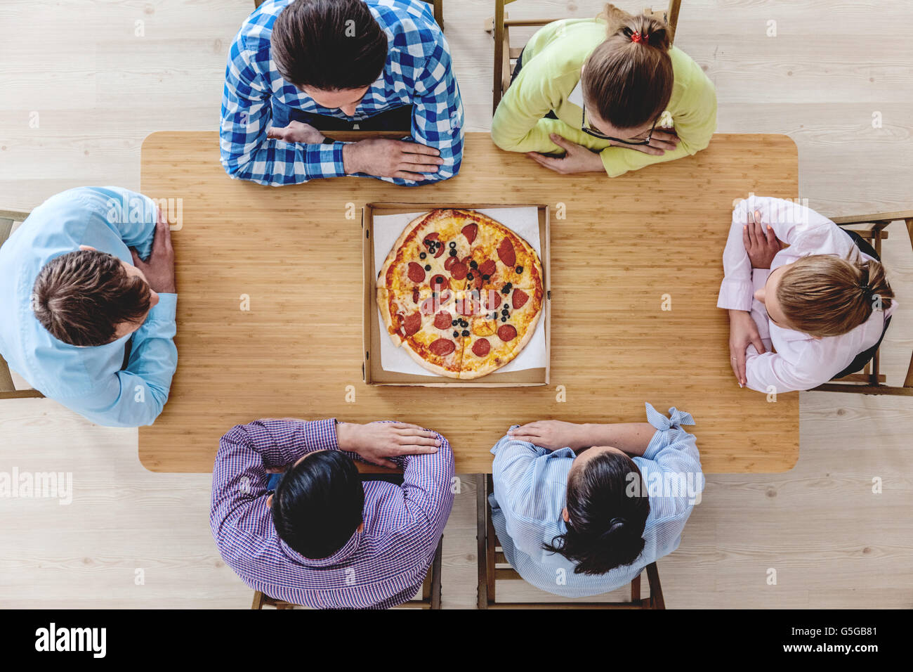 Friends sitting around the table with pizza Stock Photo - Alamy