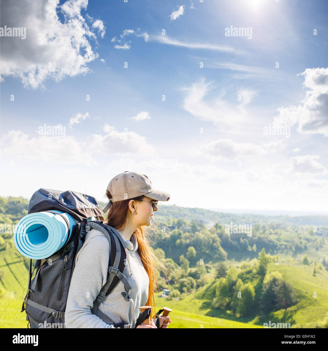 Young hiking woman with backpack standing on the top of the hill ...