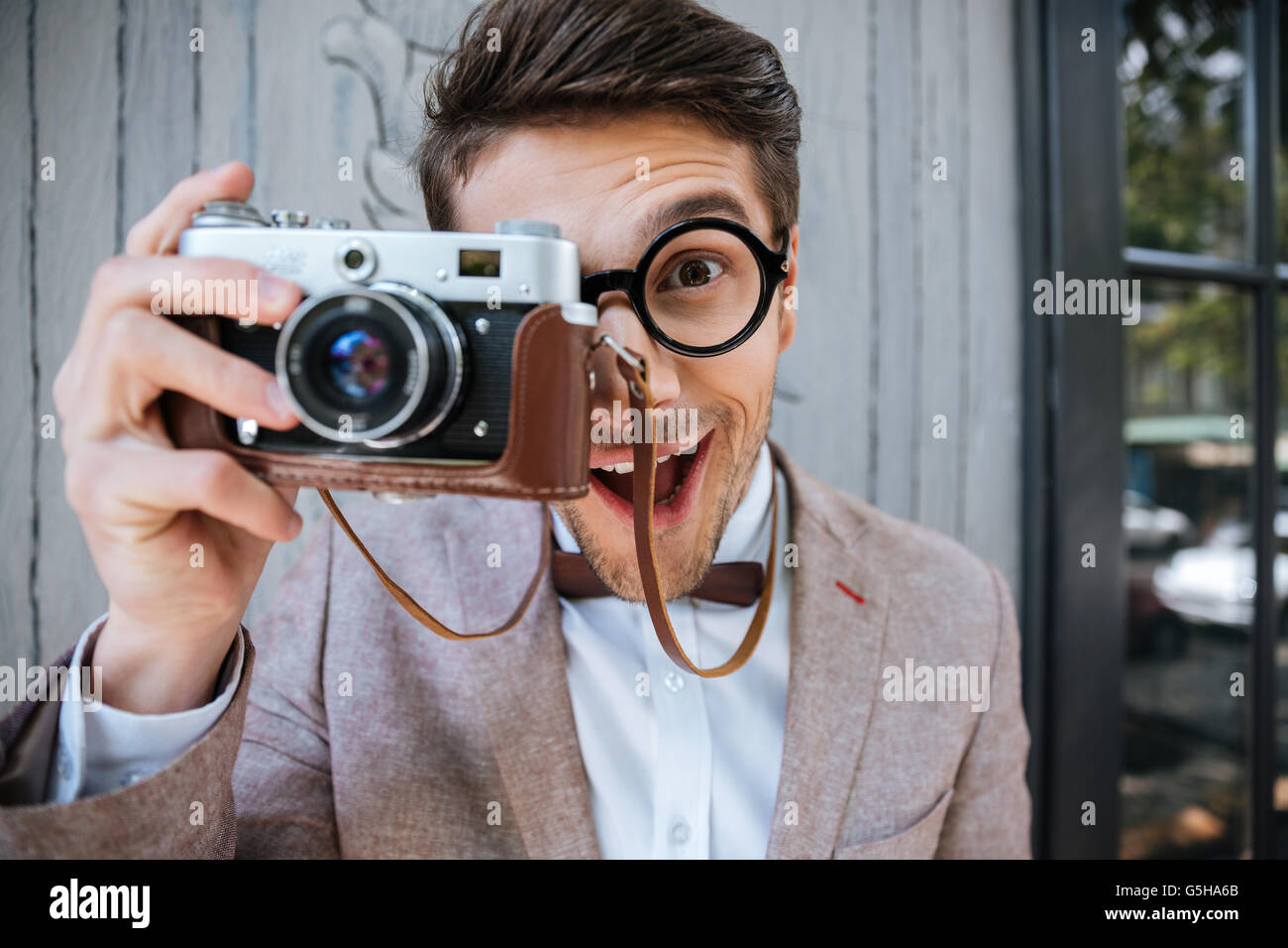 Happy funny stylish nerd holding camera outdoors Stock Photo - Alamy
