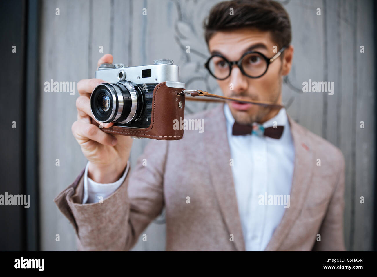 Happy funny stylish nerd holding camera outdoors Stock Photo - Alamy
