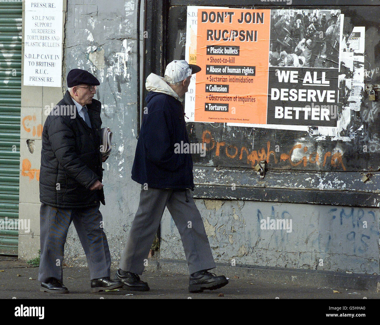 Two men walk past an anti-police posters erected in west Belfast. The ...