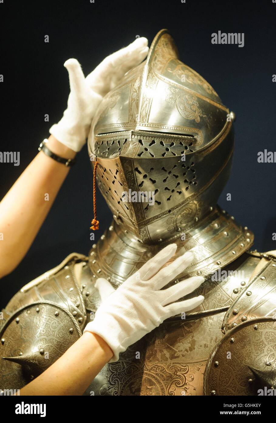 Exhibition Curator Kate Heard adjusts a suit of armour dating from ...