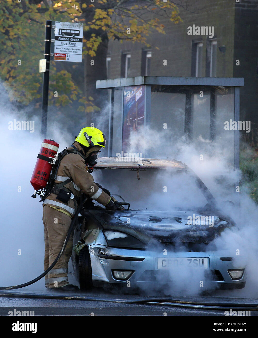 Firefighters attend to a car which was on fire on the outskirts of ...
