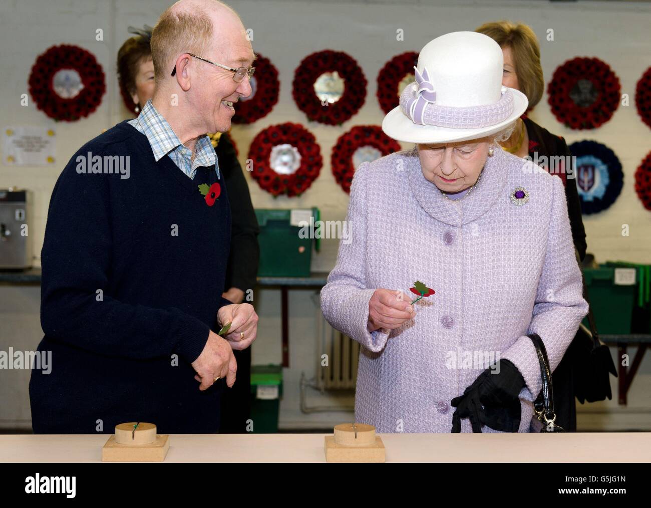 Queen Elizabeth II makes her own poppy at The Poppy Factory as see ...