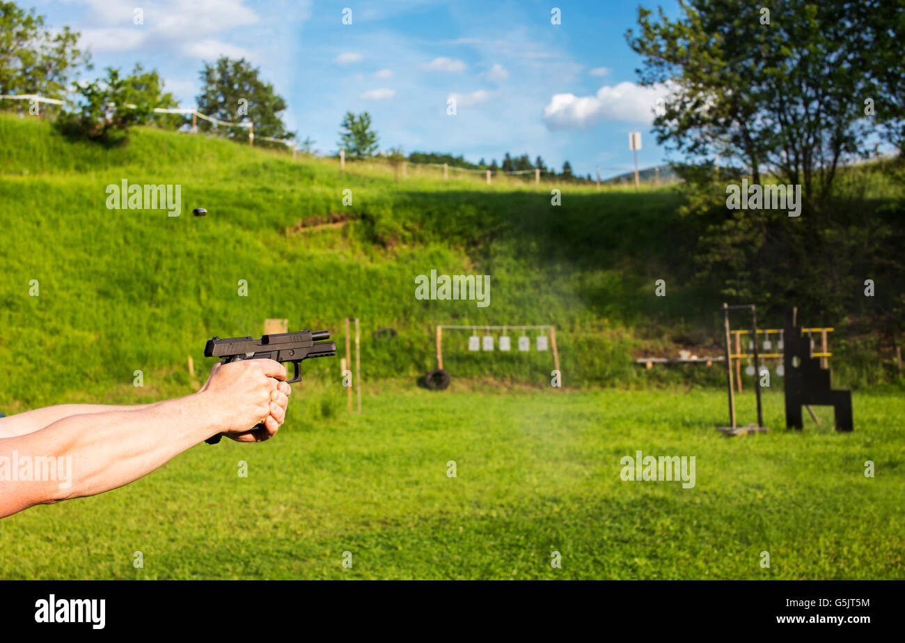 Person is holding a gun, and it's aiming at a target Stock Photo - Alamy