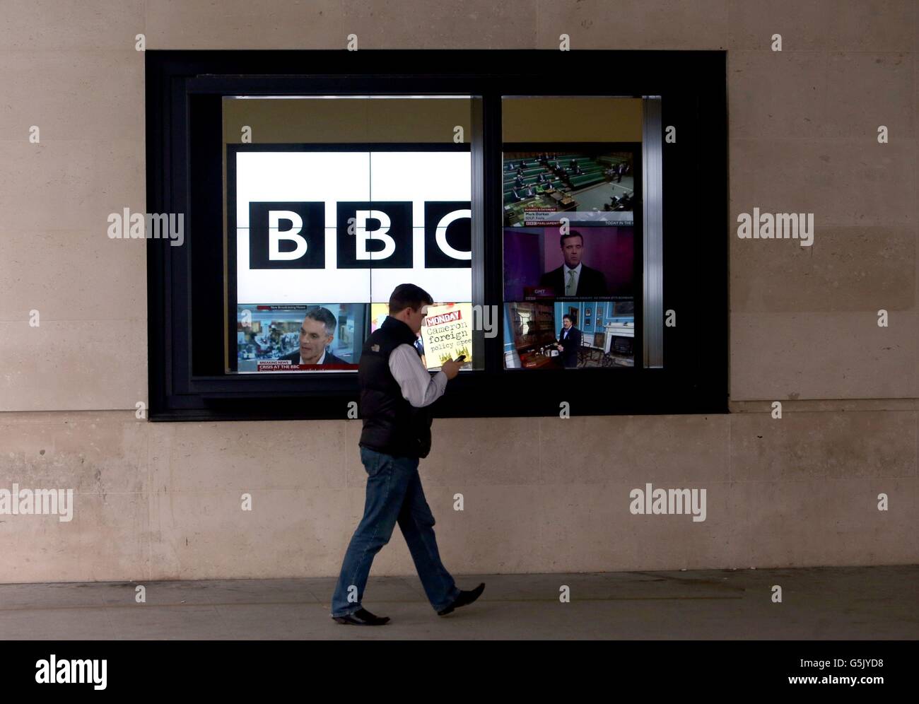 Staff walk past television screens at New Broadcasting house in central ...