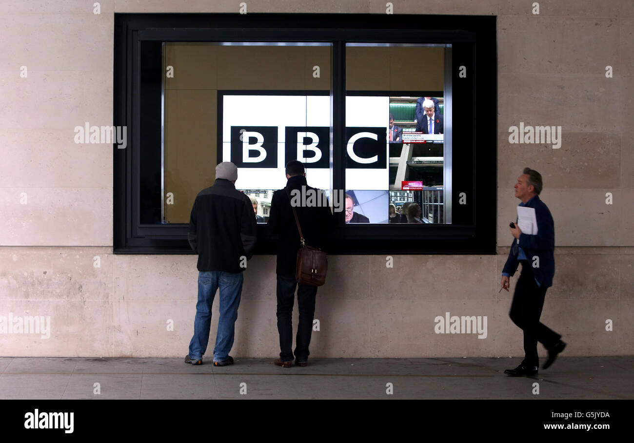 Staff walk past television screens at New Broadcasting house in central ...