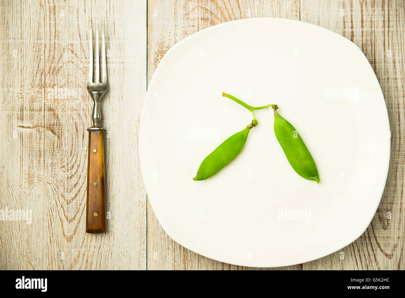Green pea pods and fork on the white plate Stock Photo - Alamy