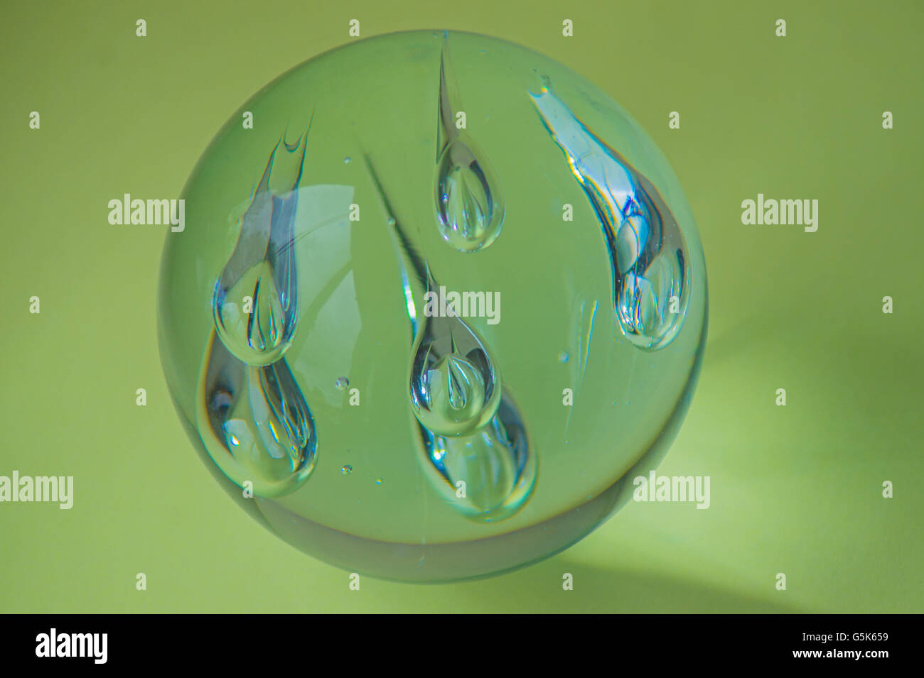 Glass transparent orb with silver comet shapes on green background ...