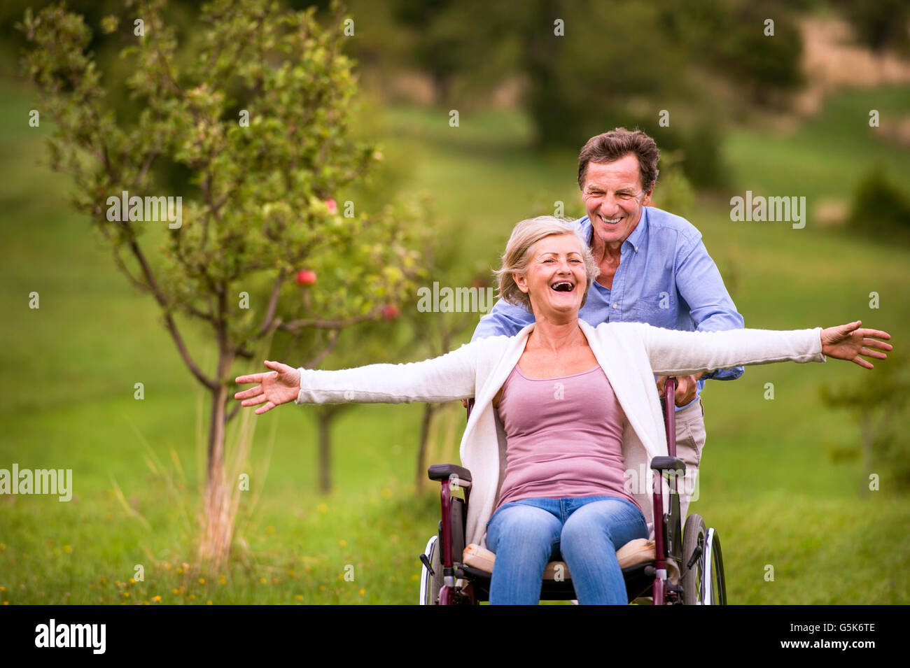 Senior man pushing woman in wheelchair, green autumn nature Stock Photo ...