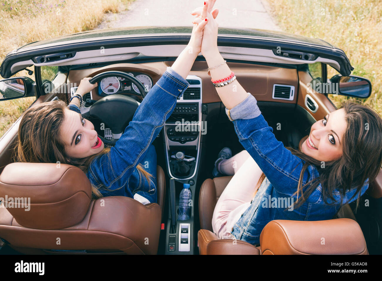Women high-fiving in convertible Stock Photo - Alamy