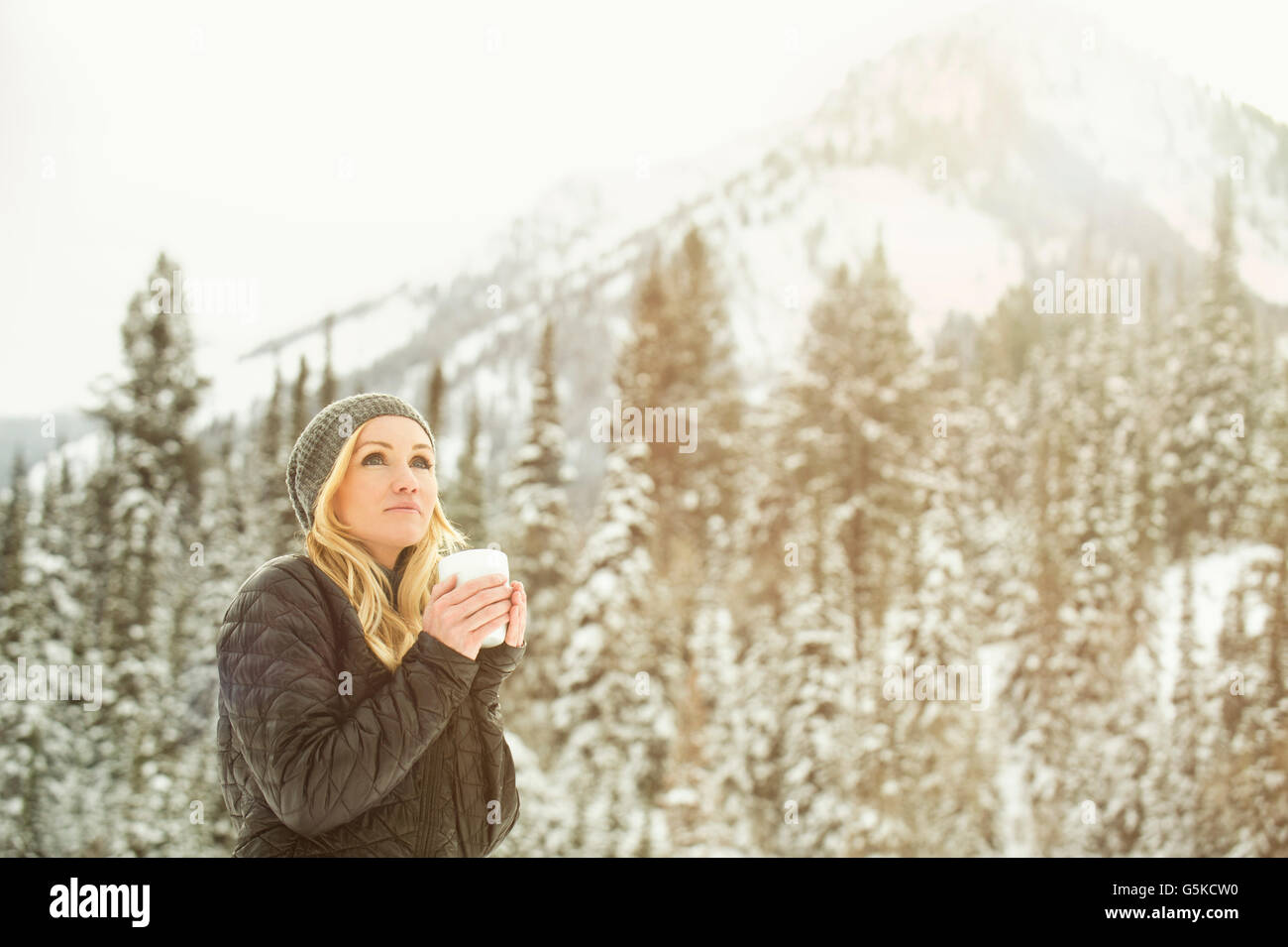 Caucasian woman drinking coffee in snow Stock Photo - Alamy