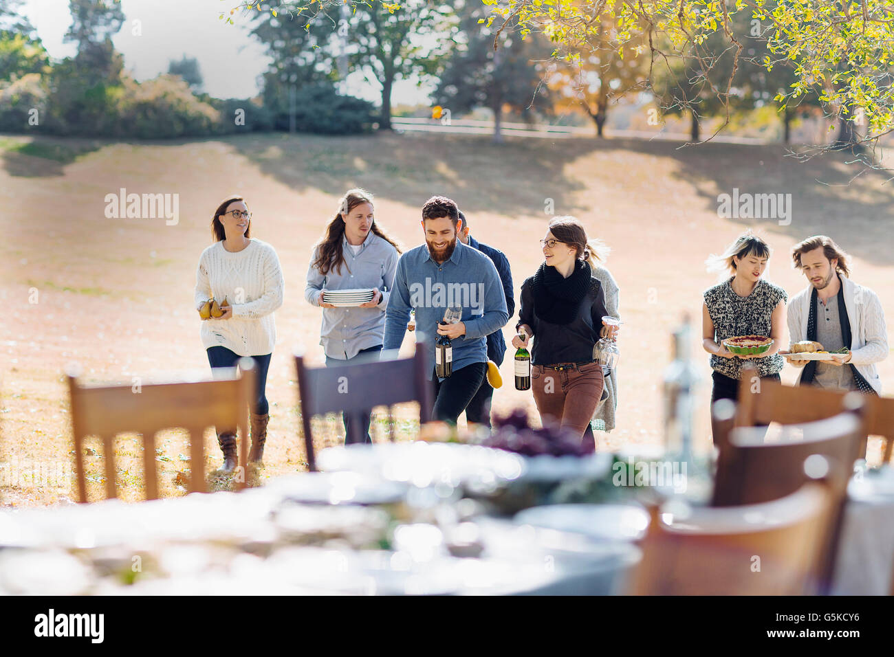 Friends carrying food to outdoor dining table Stock Photo - Alamy
