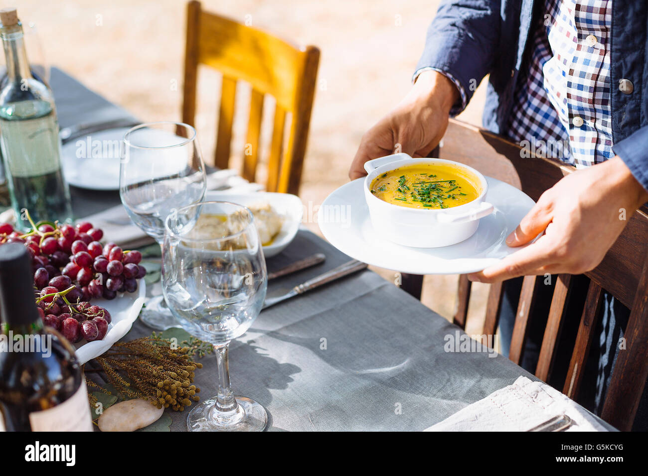 Man setting platter of soup on outdoor table Stock Photo - Alamy