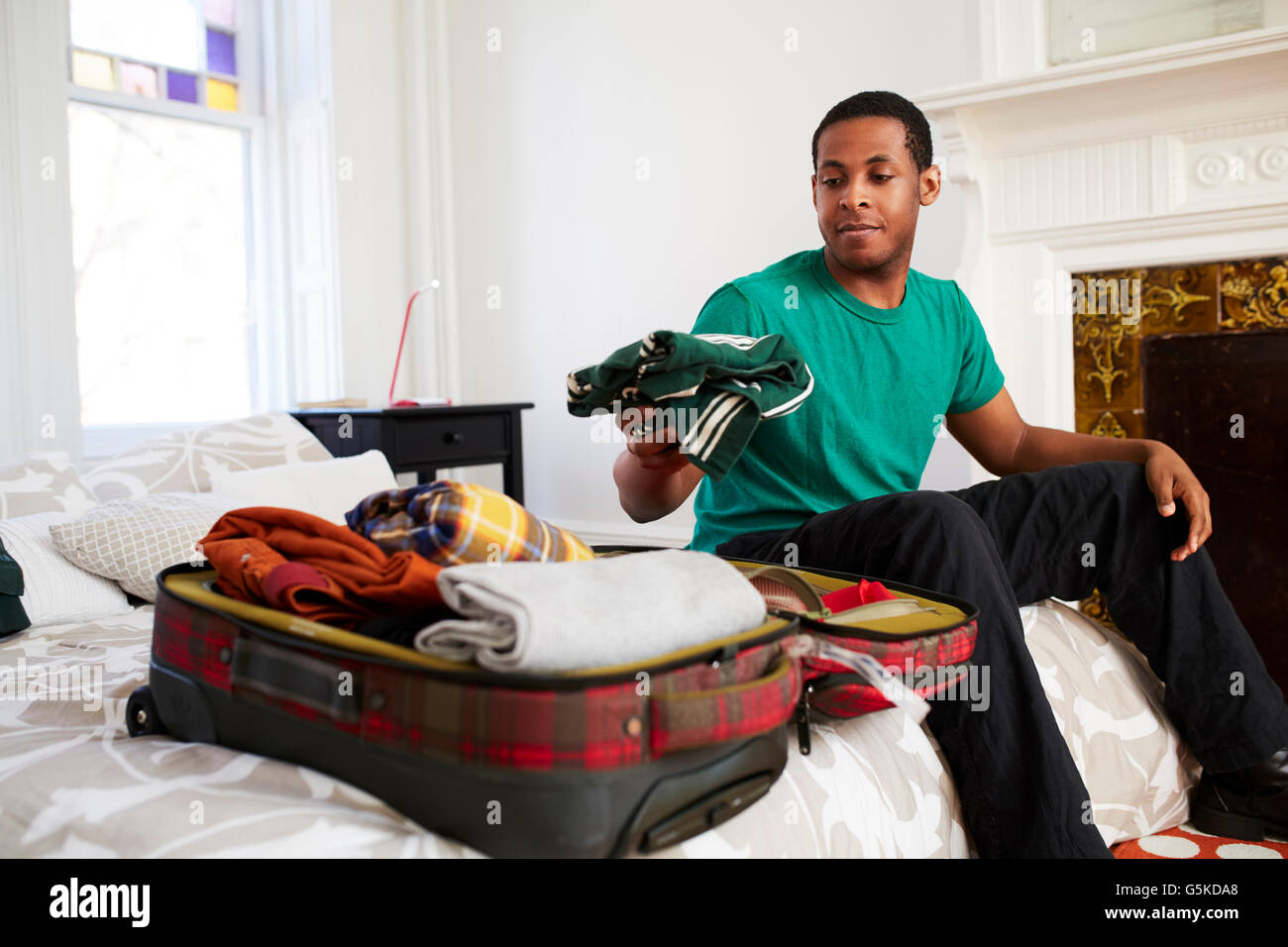 African American man packing suitcase in bedroom Stock Photo - Alamy