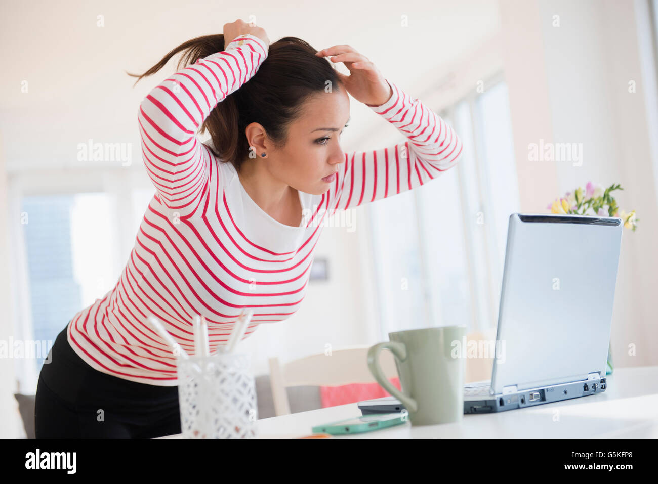 Woman styling her hair with laptop Stock Photo - Alamy