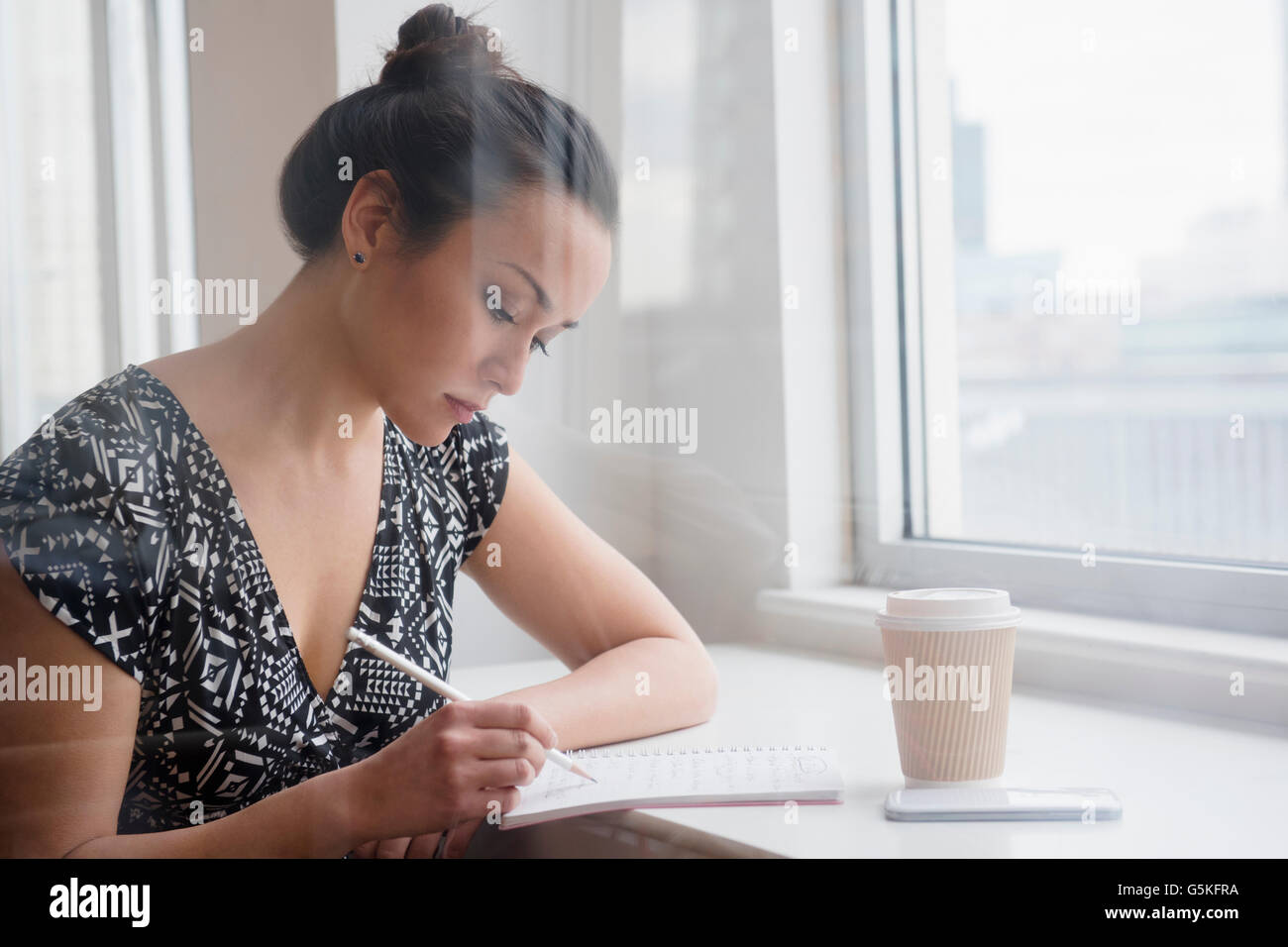 Woman writing in coffee shop Stock Photo - Alamy