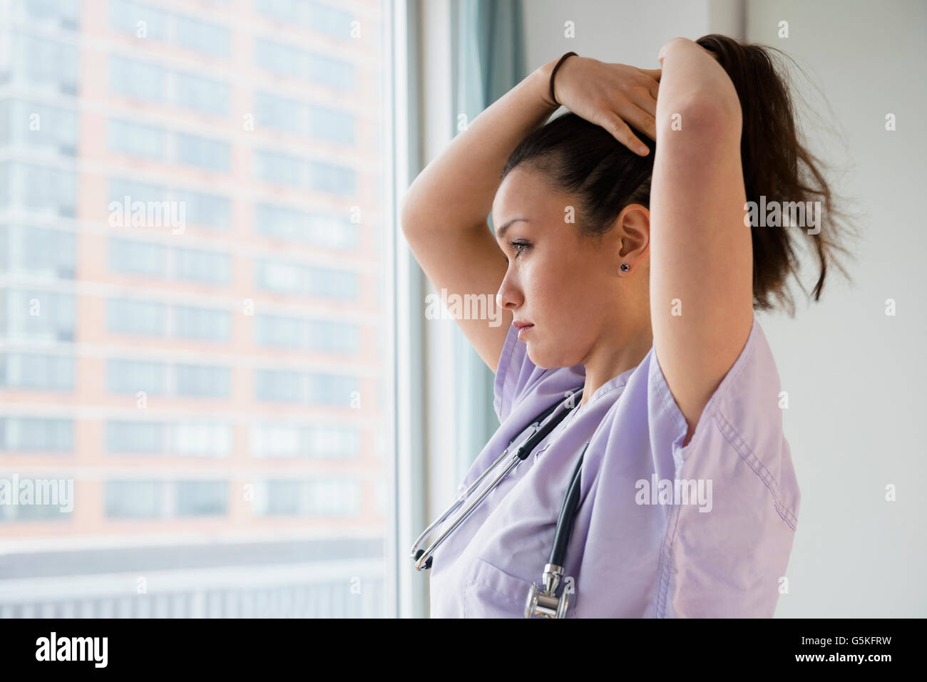 Nurse tying her hair up in hospital Stock Photo - Alamy