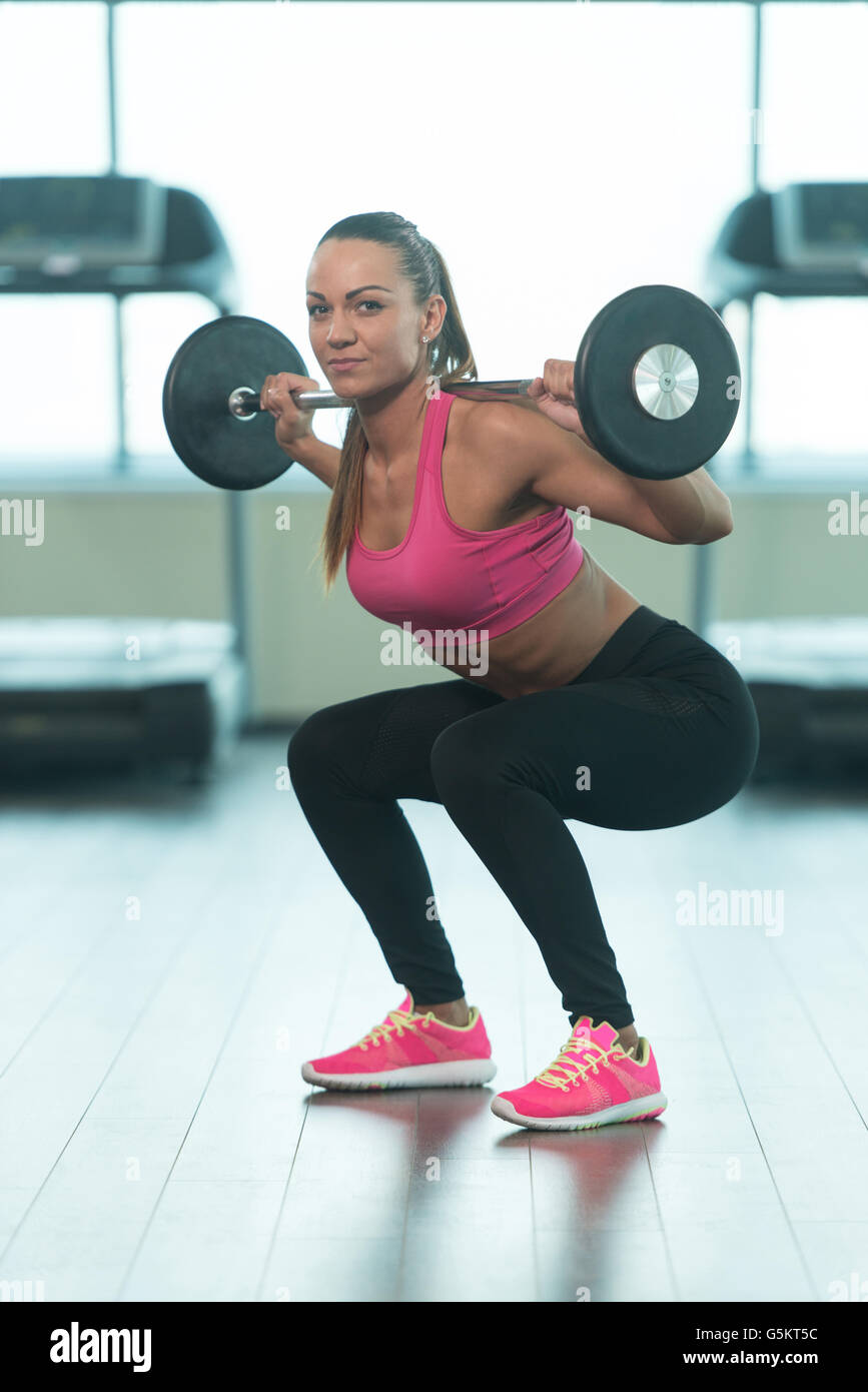 Healthy Fitness Woman Working Out Legs With Barbell In A Gym - Squat ...
