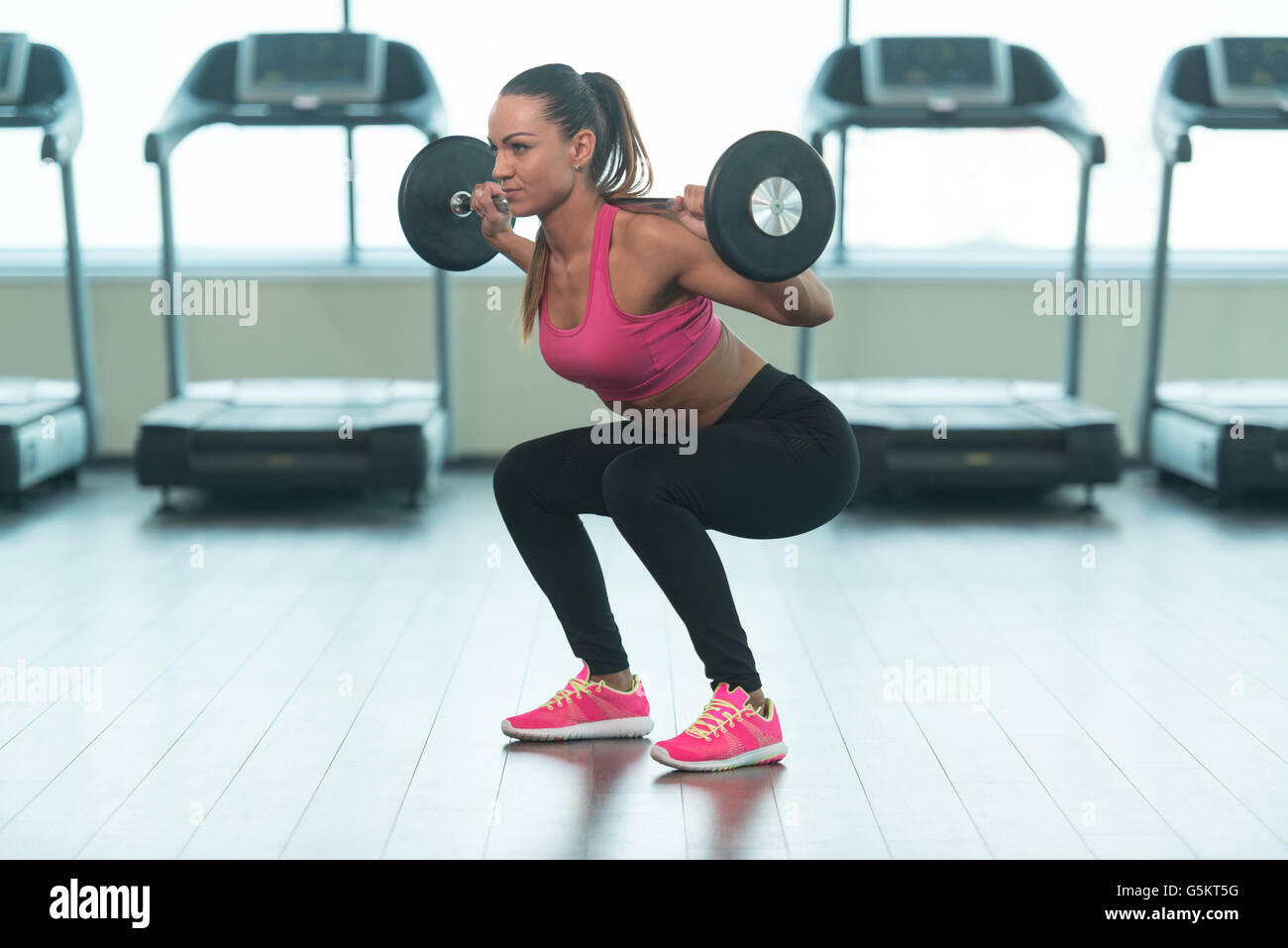 Healthy Fitness Woman Working Out Legs With Barbell In A Gym - Squat ...