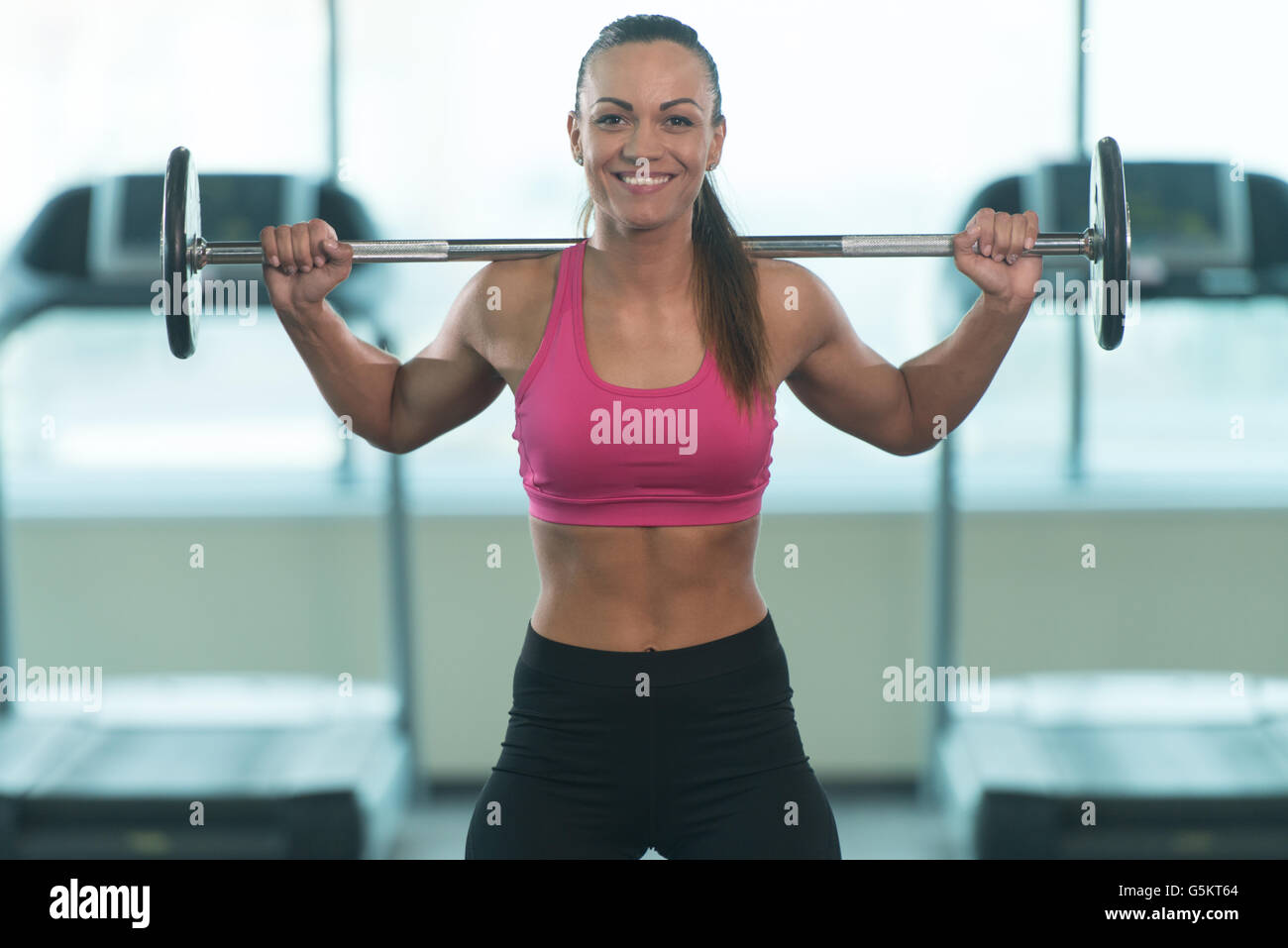 Young Woman Working Out Legs With Barbell In A Gym - Squat Exercise ...