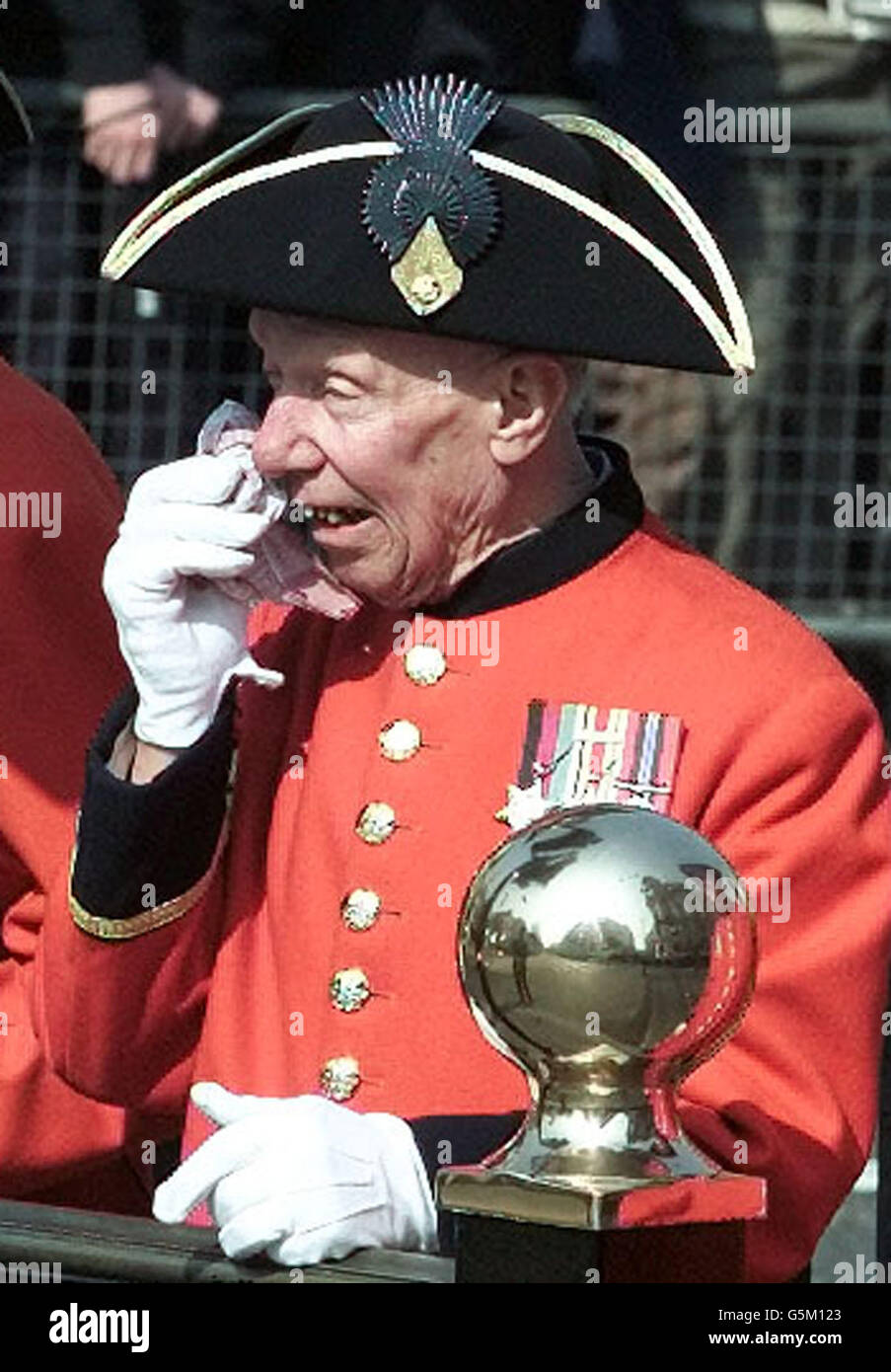 A Chelsea pensioner wipes his face in Whitehall during the ceremonial ...
