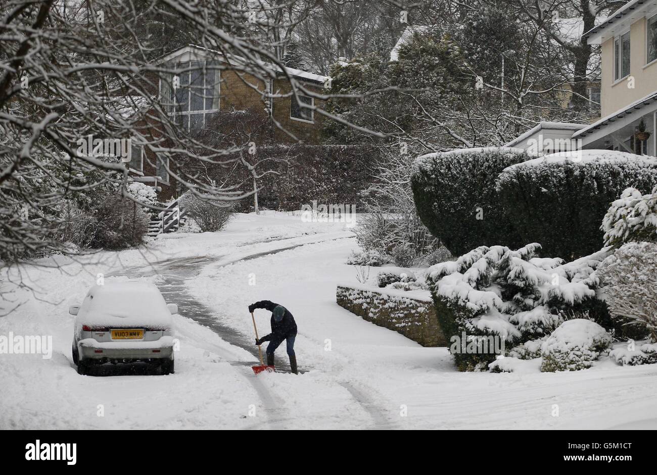 A man uses a snow shovel to clear snow from a road in Greenfield near ...
