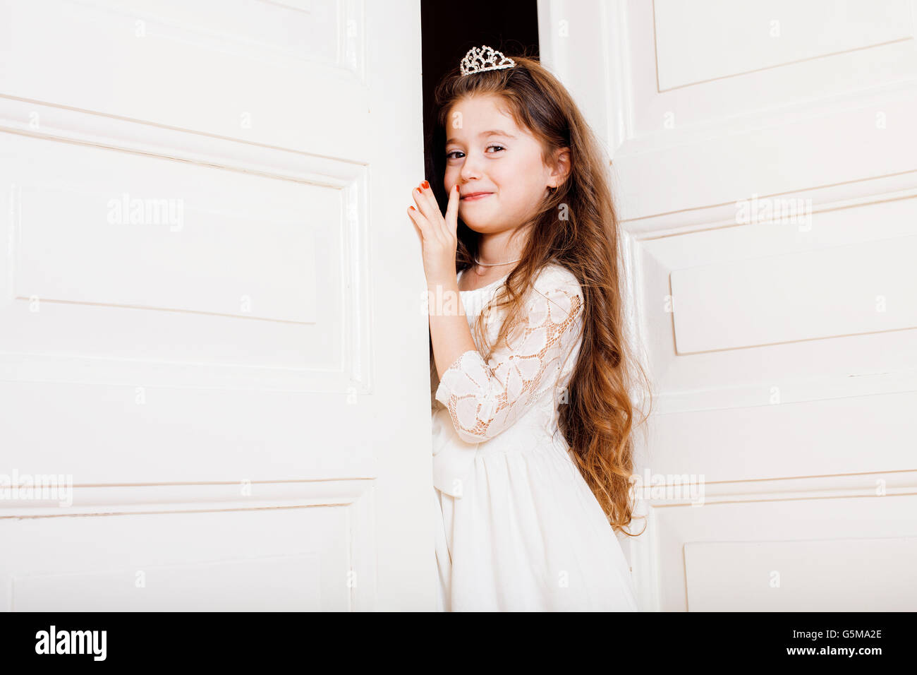 little cute girl at home, opening door well-dressed in white dress ...