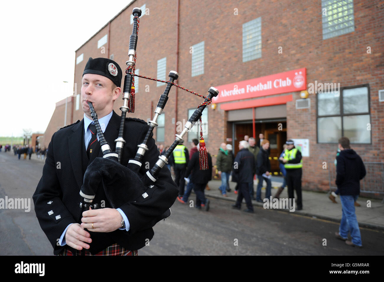 A traditional bagpipe player plays for the arriving fans outside the ...