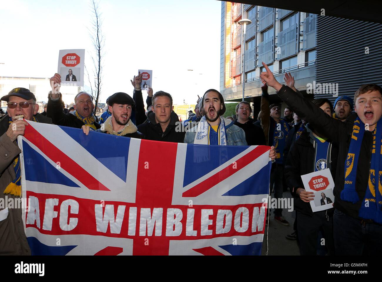 AFC Wimbledon fans hold up a flag supporting their team outside stadium ...