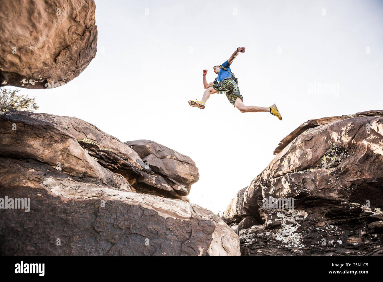 Caucasian teenage boy leaping over boulders Stock Photo - Alamy