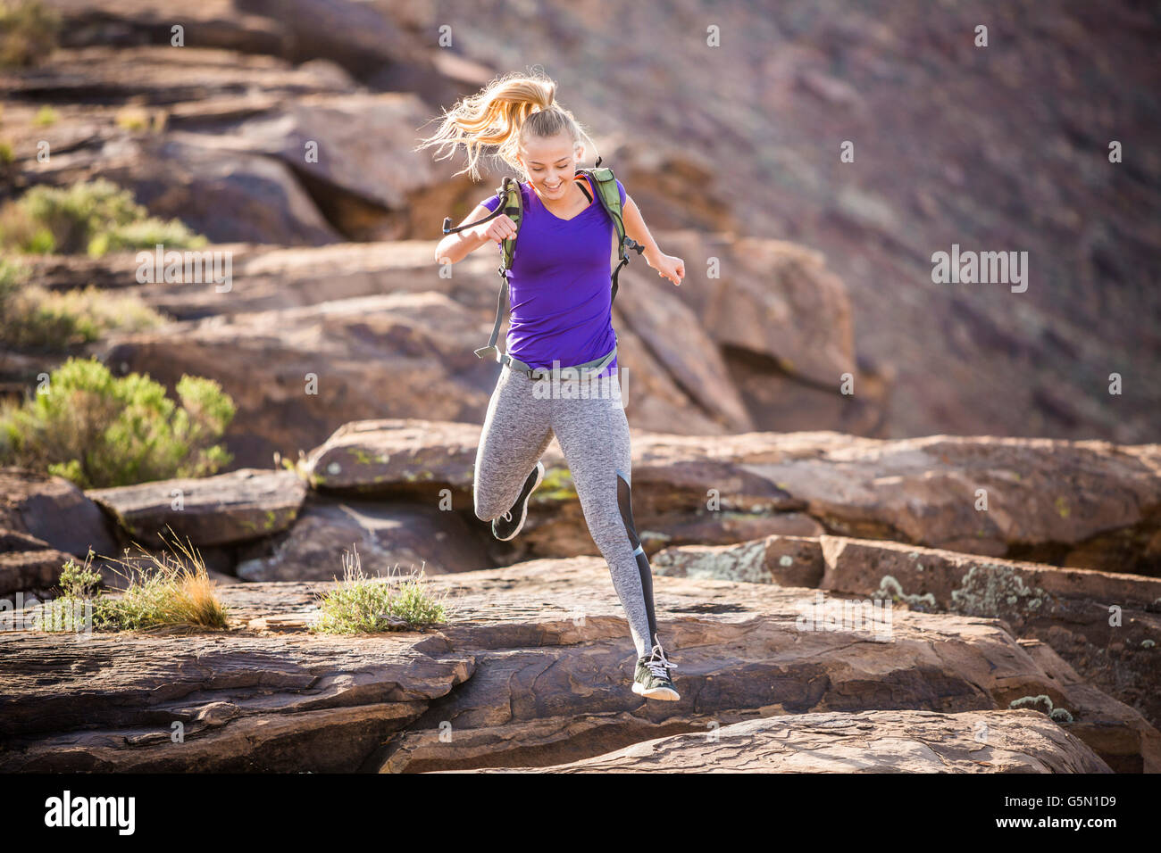 Caucasian woman running on rock formation Stock Photo - Alamy