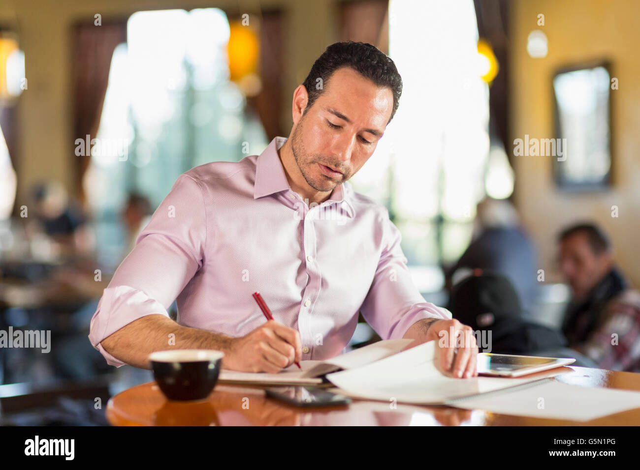 Hispanic businessman writing in coffee shop Stock Photo - Alamy