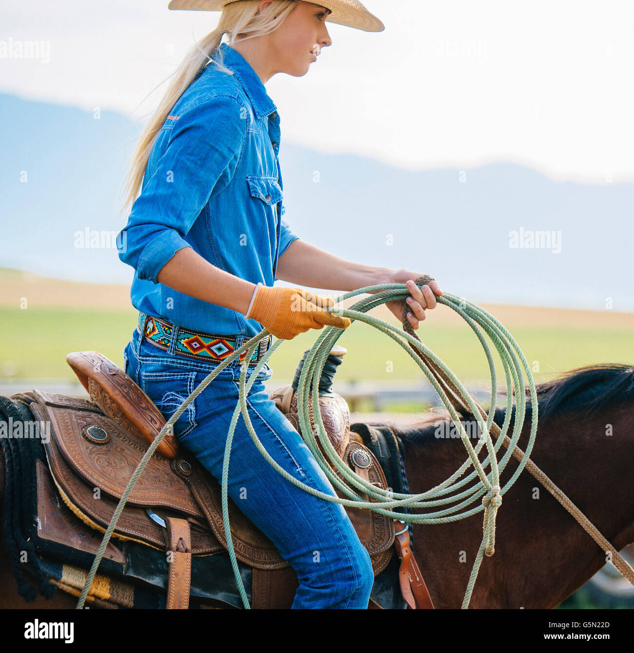 Caucasian cowgirl holding lasso on horseback Stock Photo - Alamy