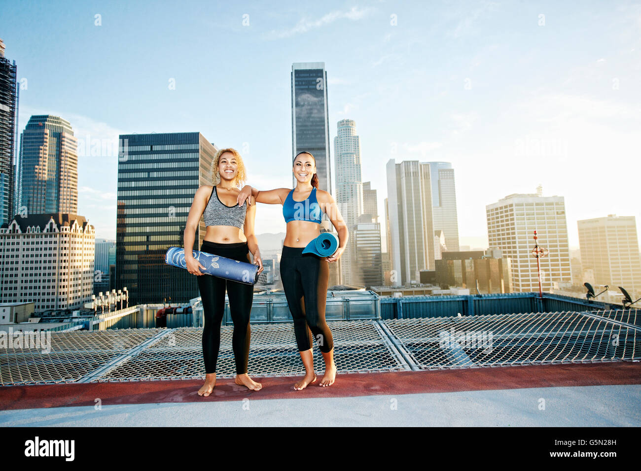 Women holding yoga mats on urban rooftop Stock Photo - Alamy