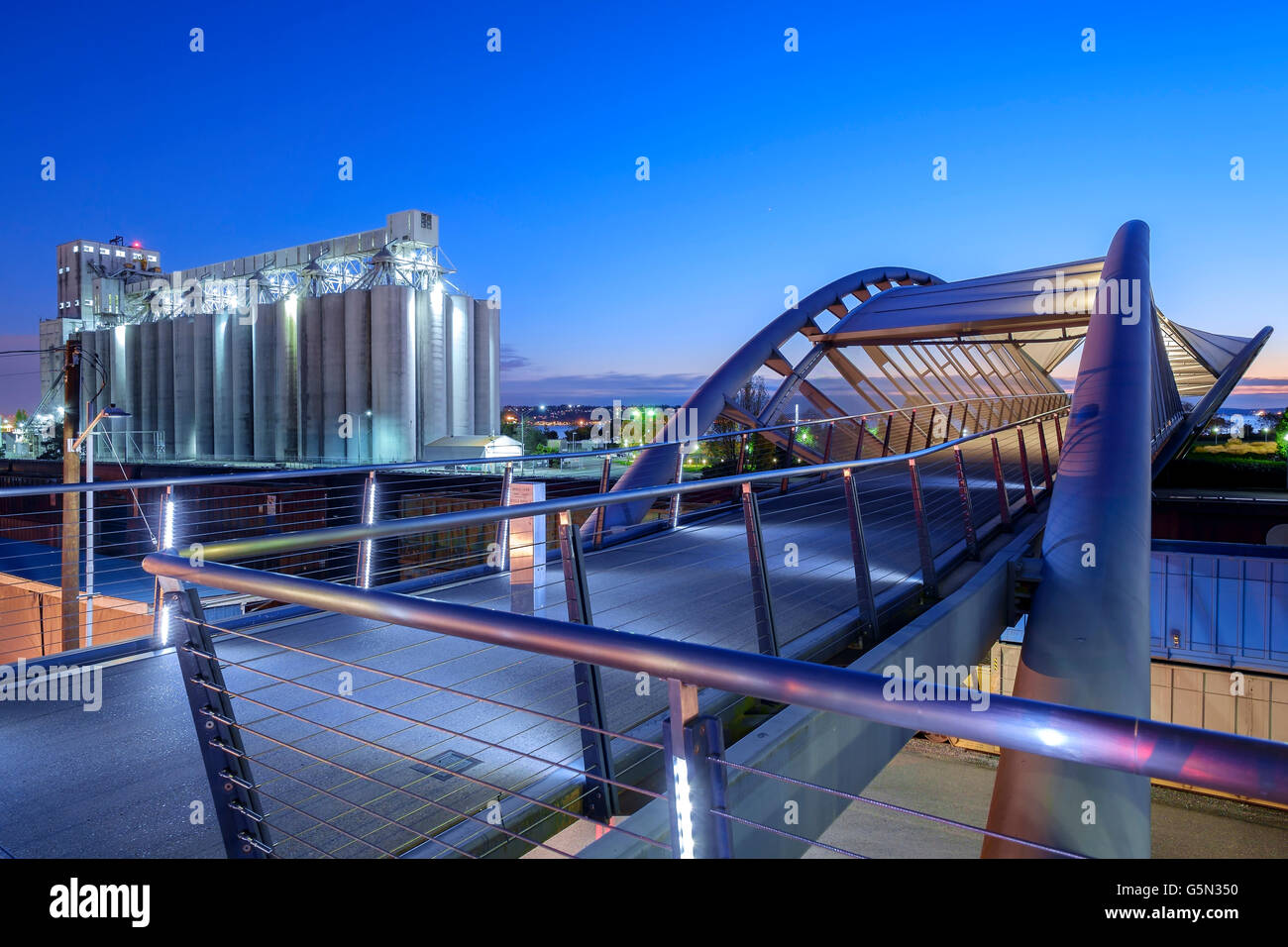 Pedestrian bridge and factory lit up at night Stock Photo - Alamy