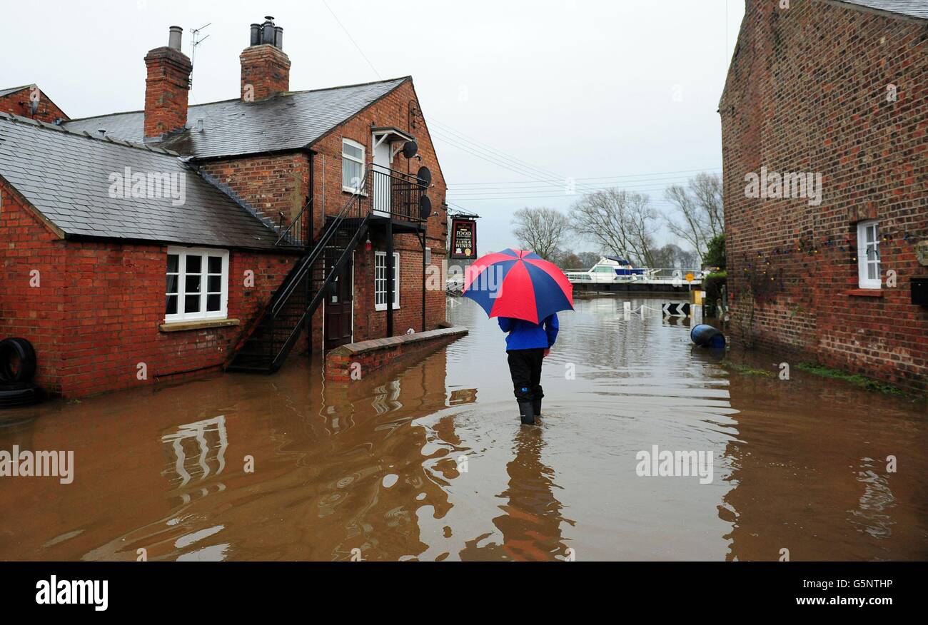 A man makes his way through flood water outside the Ship Inn Pub in ...