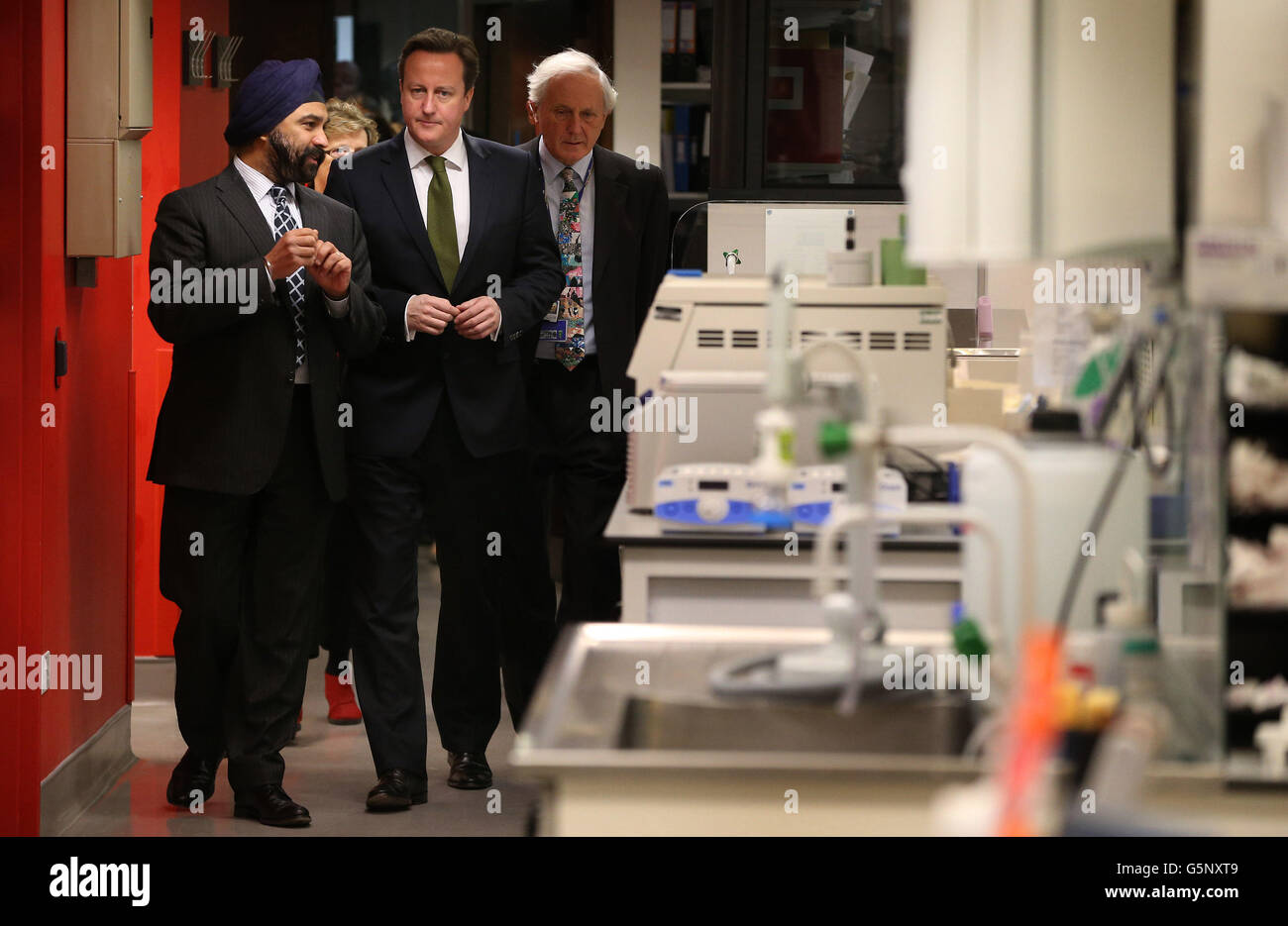 Prime Minister David Cameron (centre) walks with Dr Harpal Kumar (left ...