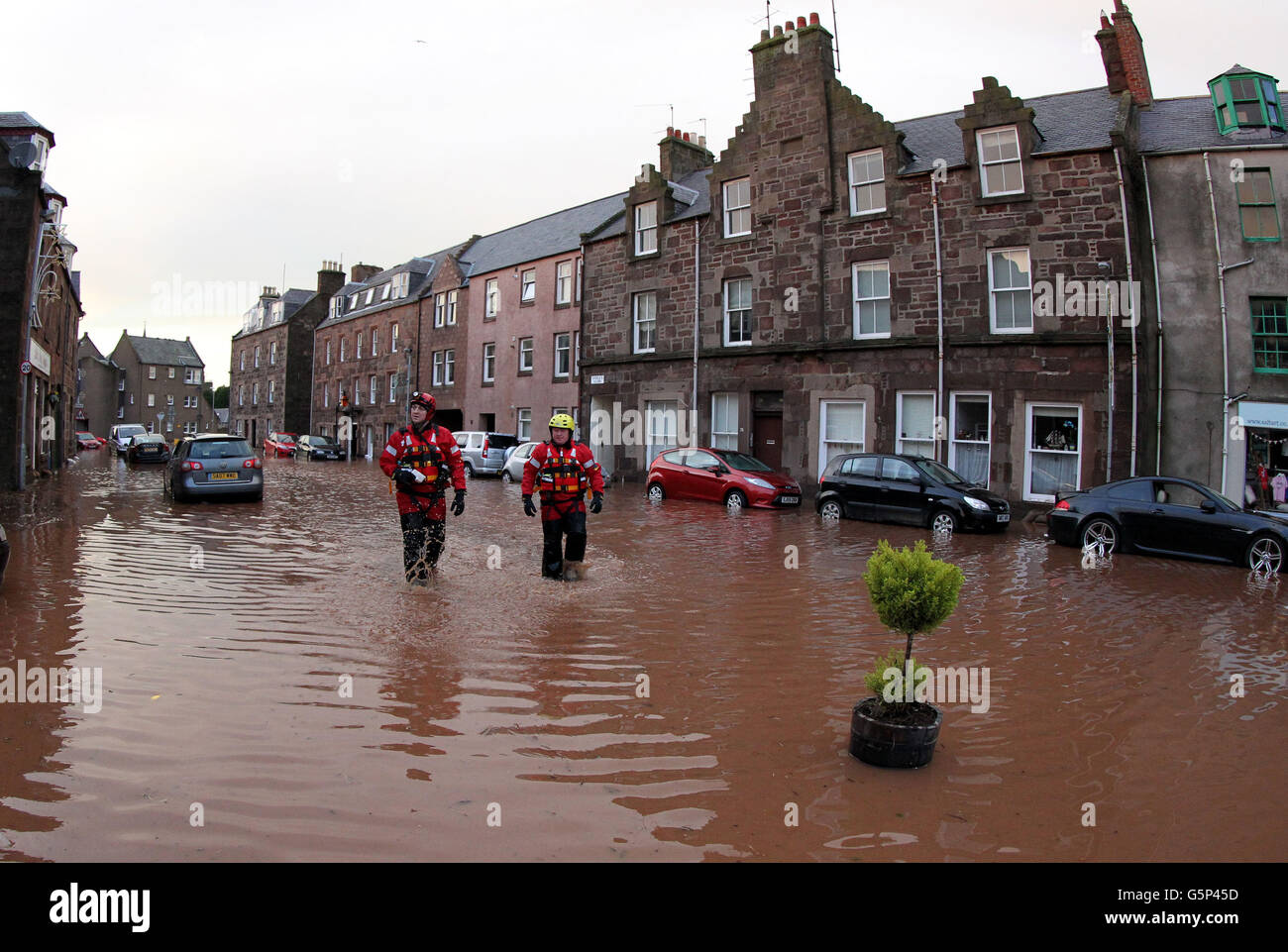 Fireman walk through floodwater on the high street in Stonehaven, near ...