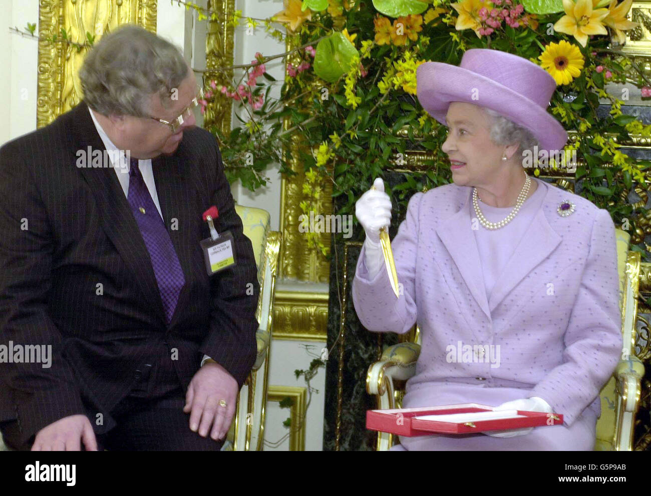 Queen Elizabeth II holds a gold letter opener after it was given to her ...