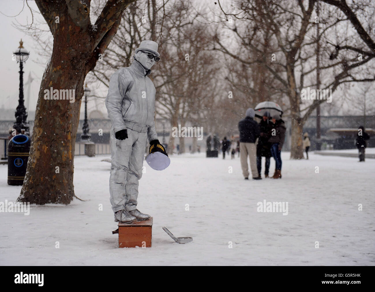 A human statue poses for the public as heavy snow falls in London Stock ...